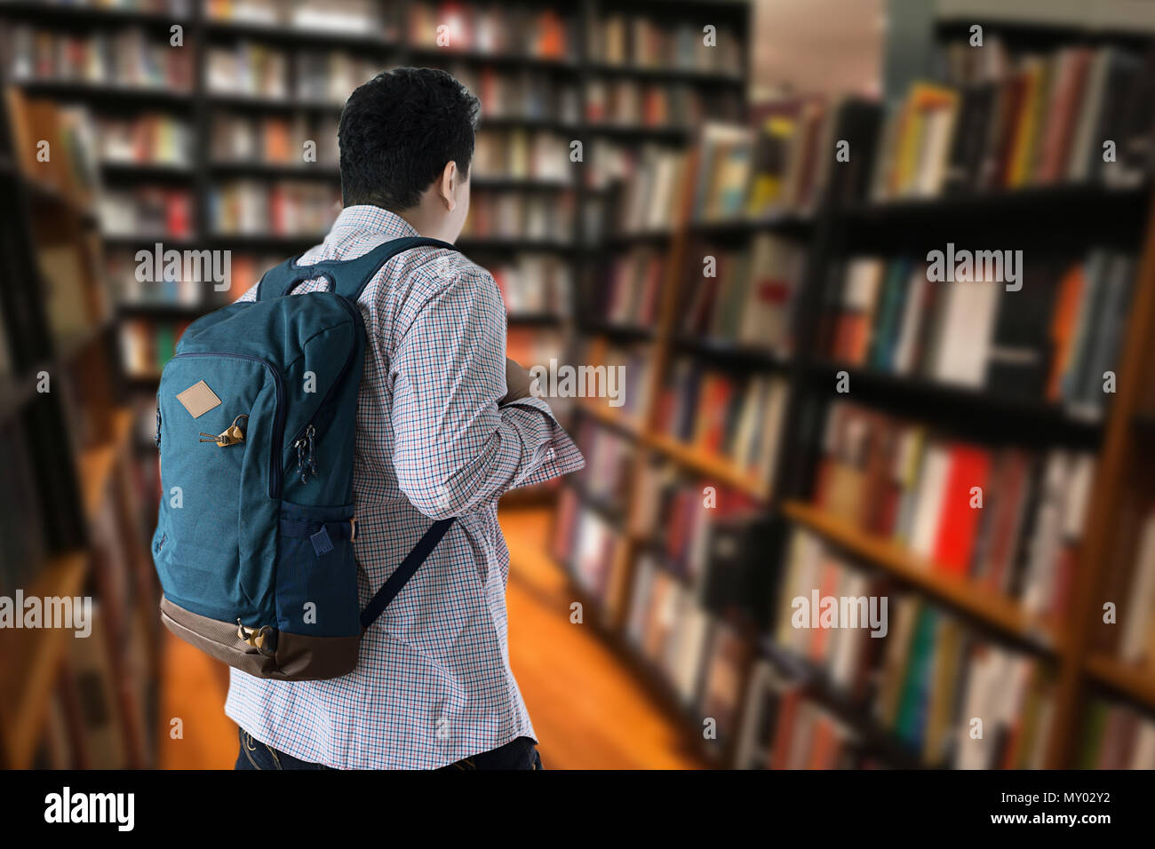 Happy Student with backpack go to holding books library bookshelves ...