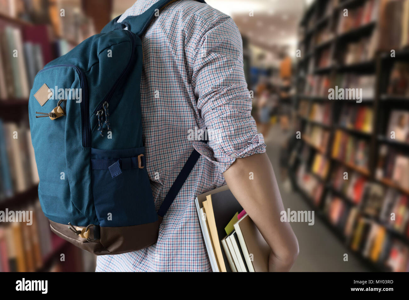 Happy Student with backpack go to holding books library bookshelves ...