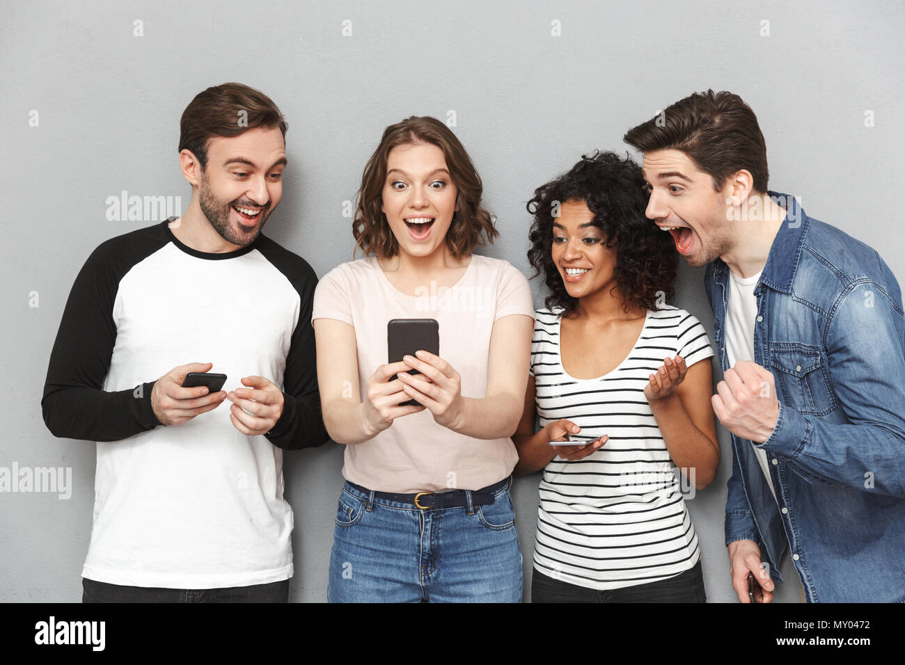 Photo of shocked happy group of friends standing isolated over grey ...