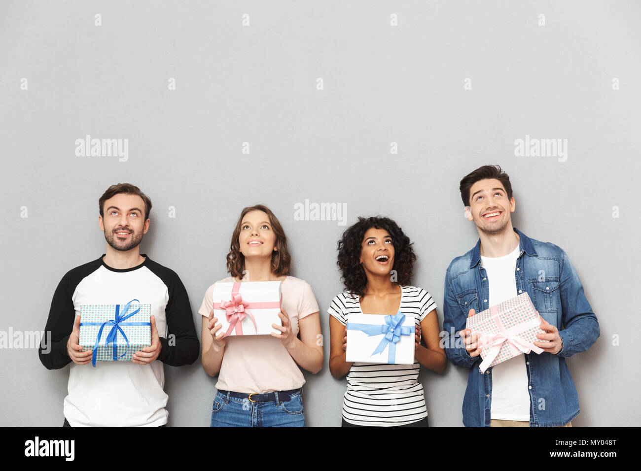 Photo of positive group of friends standing isolated over grey wall ...