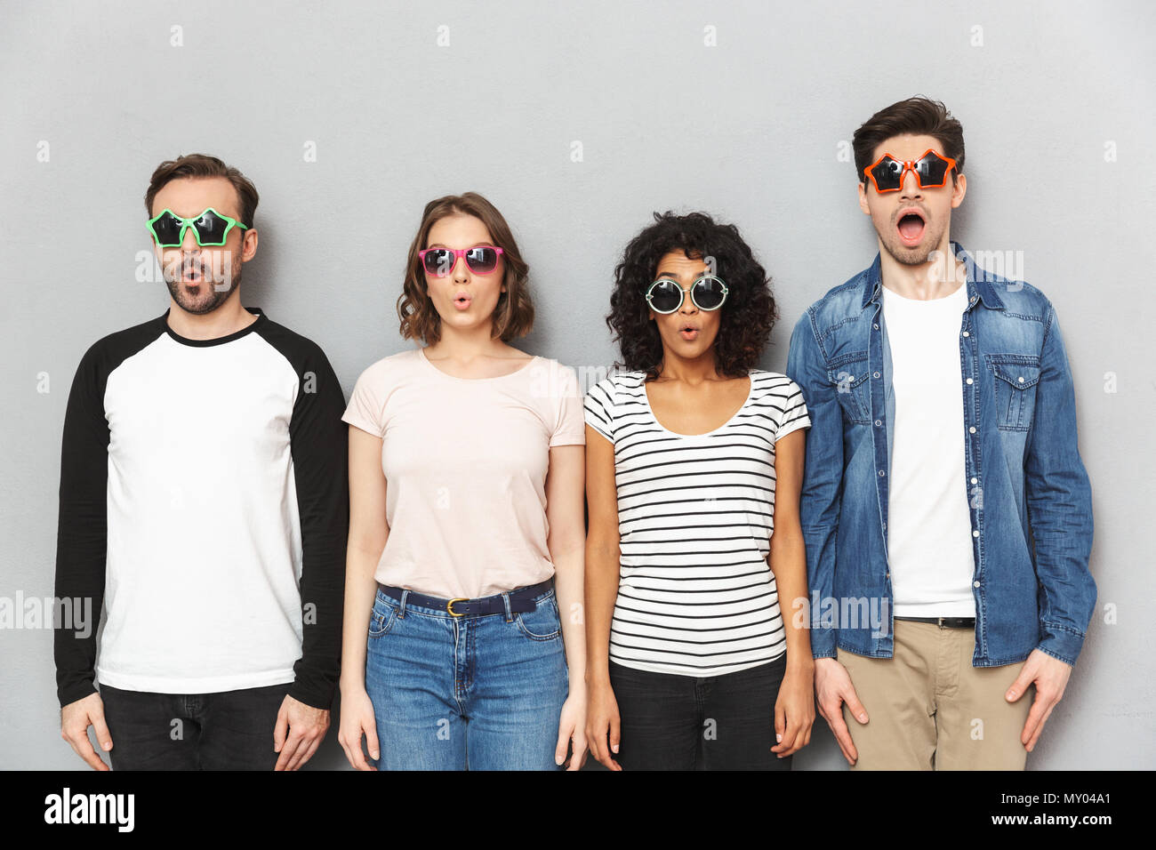 Image of shocked group of friends standing isolated over grey wall ...