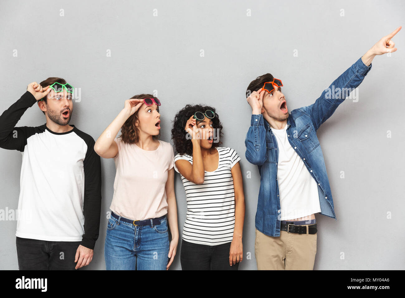 Image of shocked group of friends standing isolated over grey wall ...