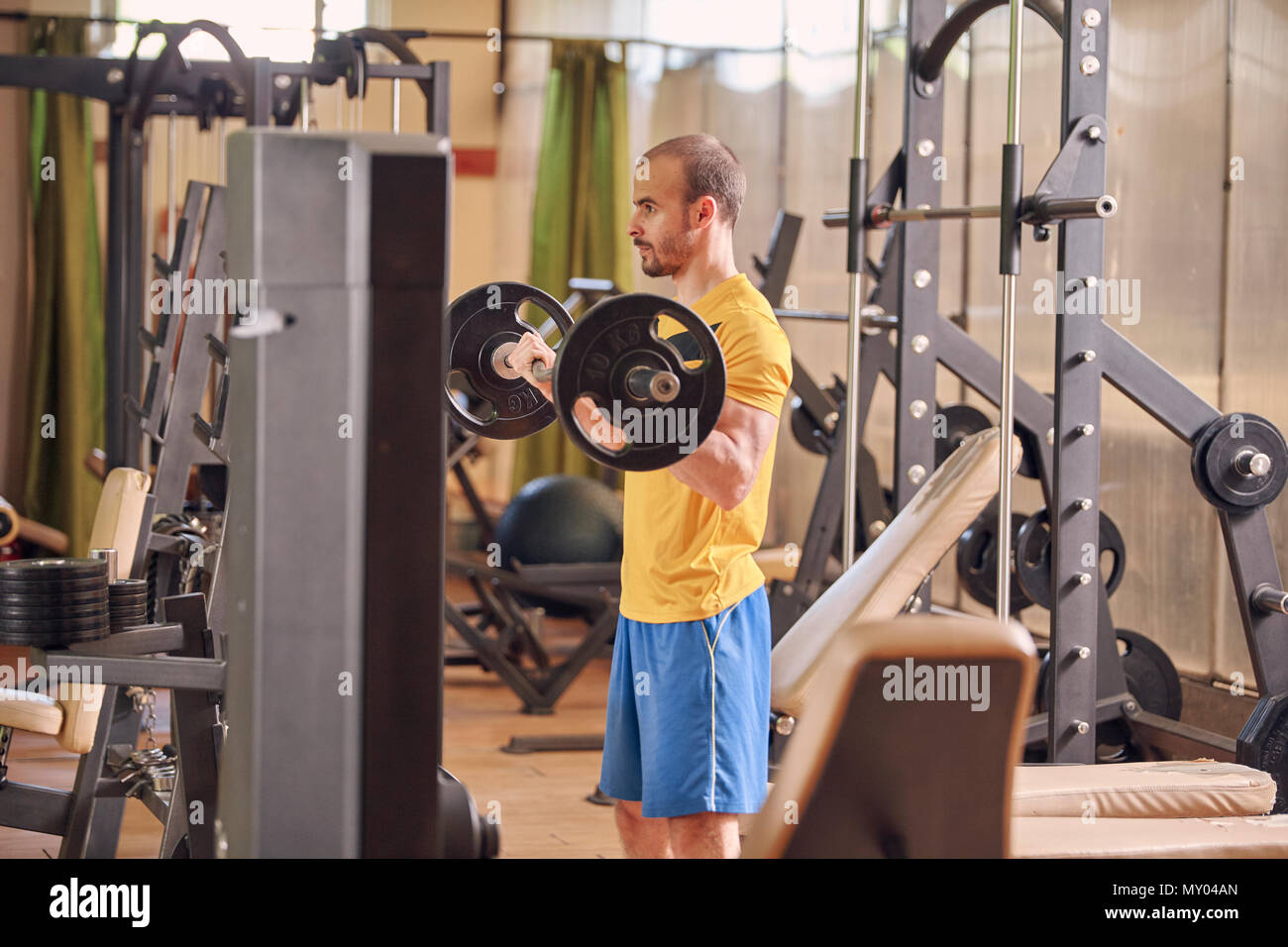 one young man, weight exercise, gym indoors exercise equipemnt, holding ...