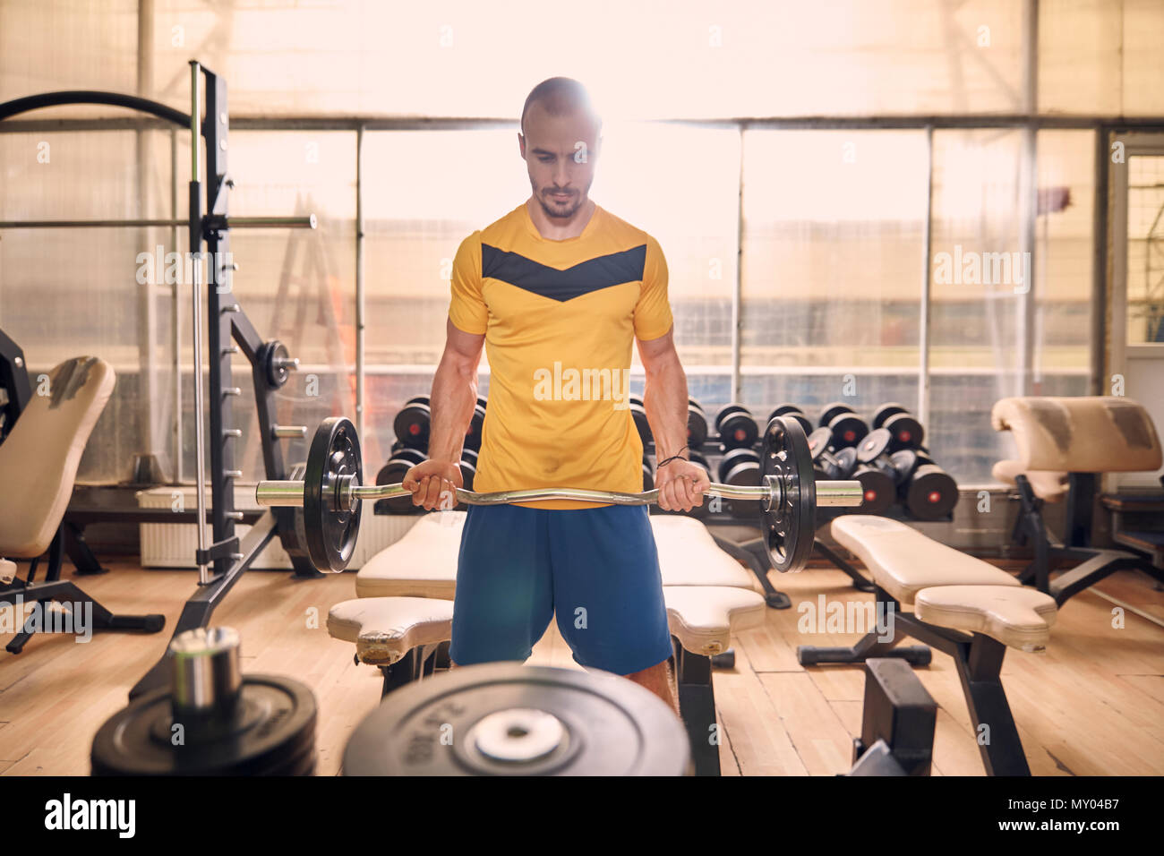 one young man, looking down, sport clothes, in old beaten up gym ...