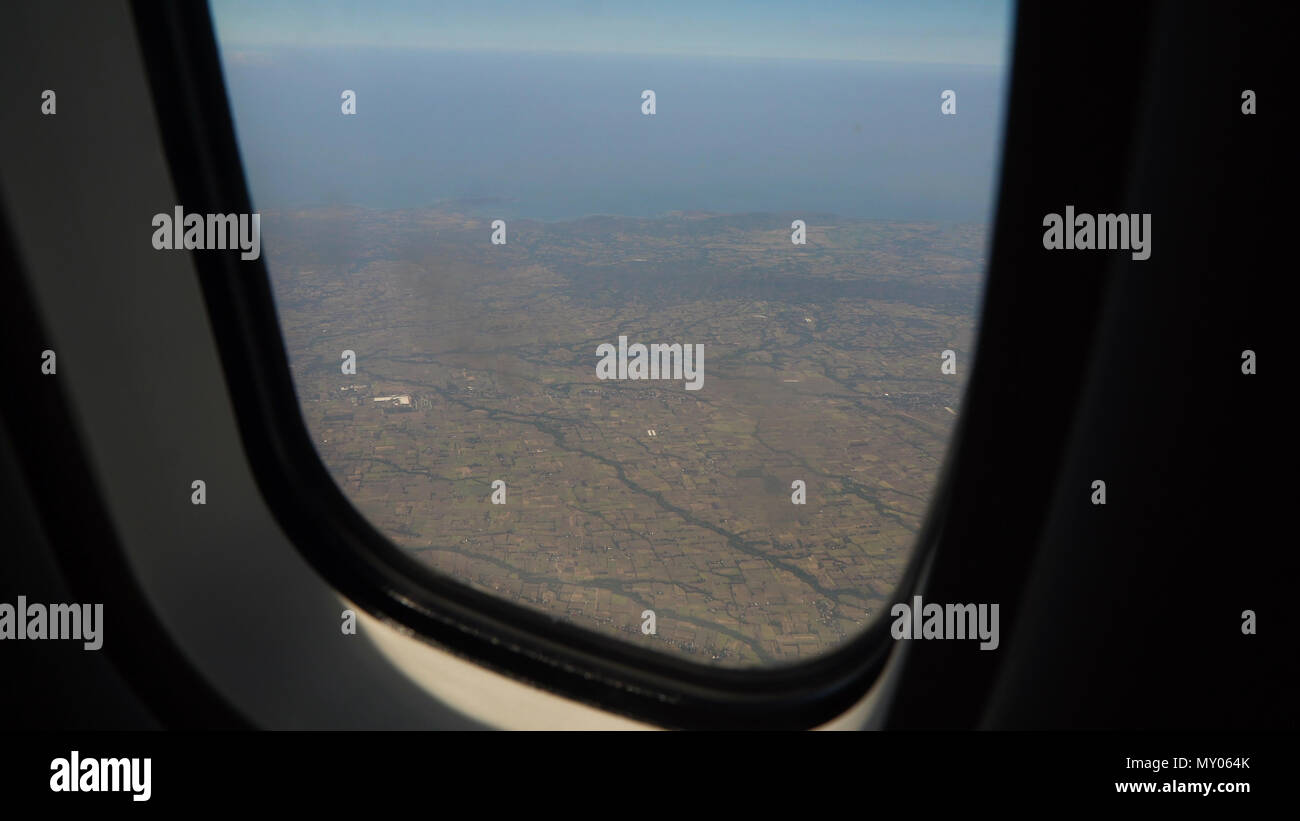 View through an airplane window on the tropical island, ocean, sky and ...