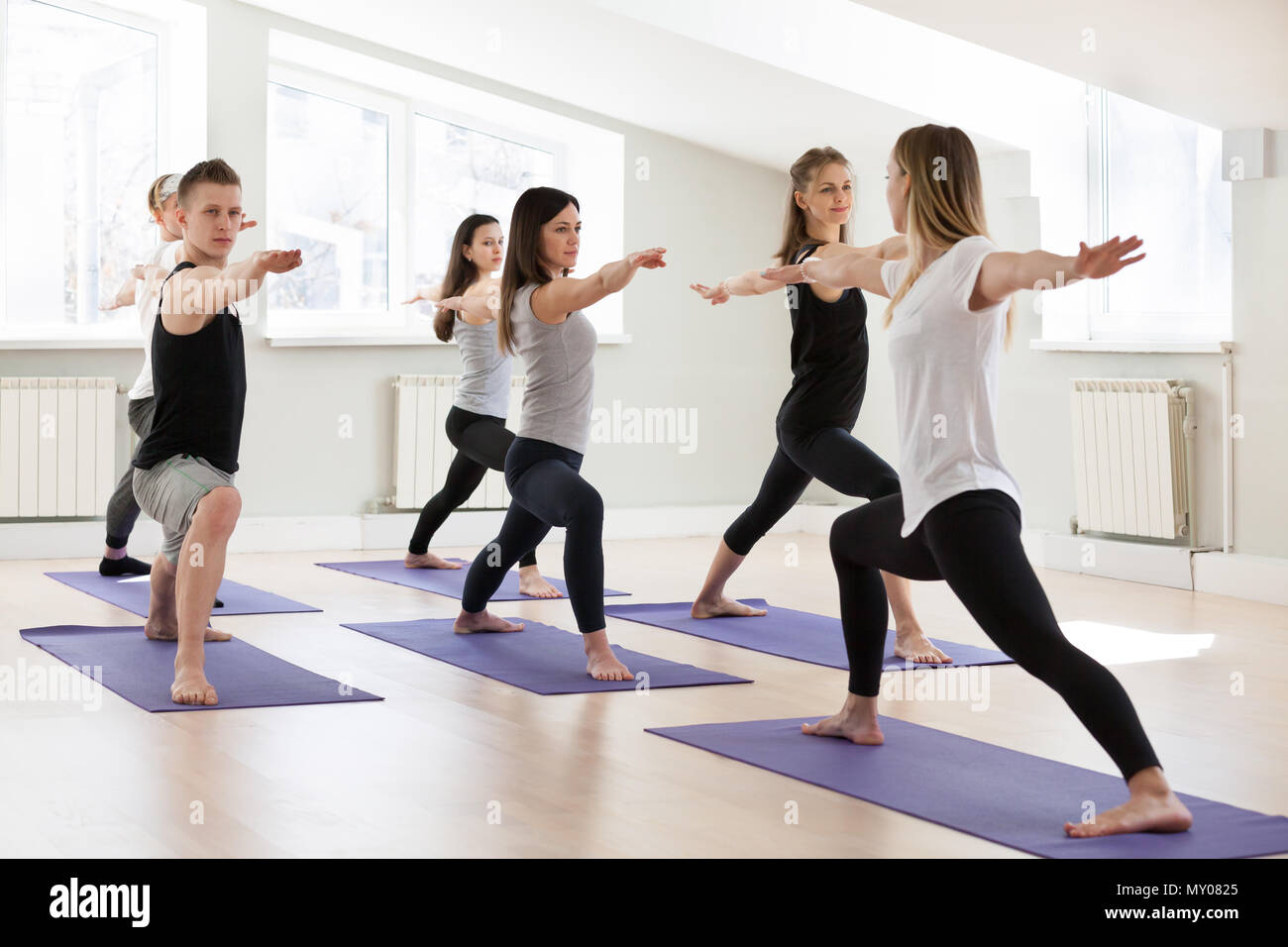 Group of young sporty people practicing yoga lesson with instructor ...