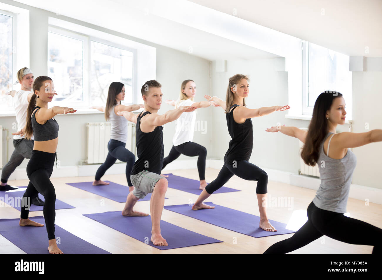 Group of sporty people practicing yoga lesson with instructor, doing ...