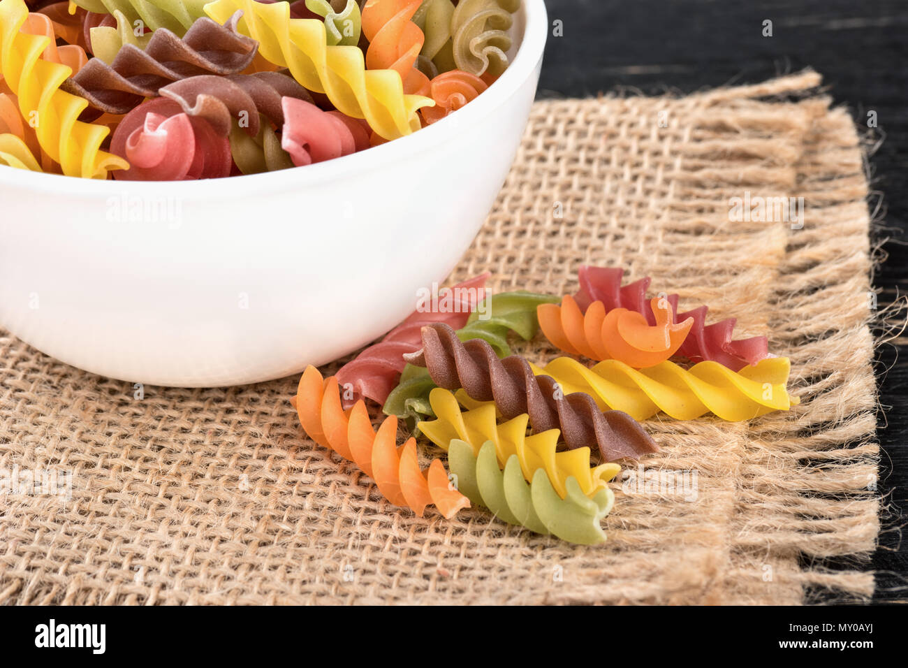 Raw colored pasta fusilli with a bowl closeup Stock Photo - Alamy