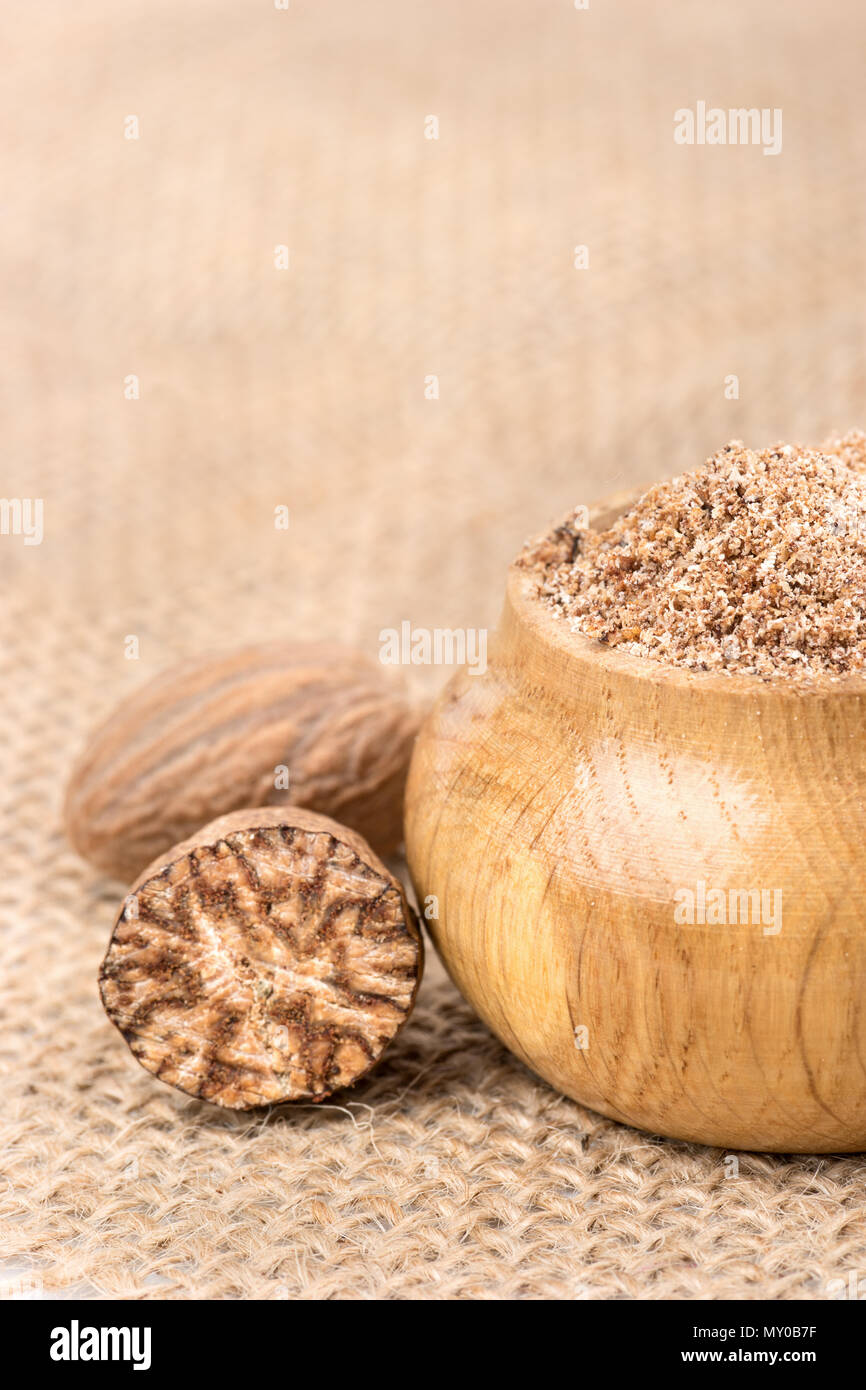 Spice nutmeg in the wooden jar on the burlap closeup Stock Photo - Alamy