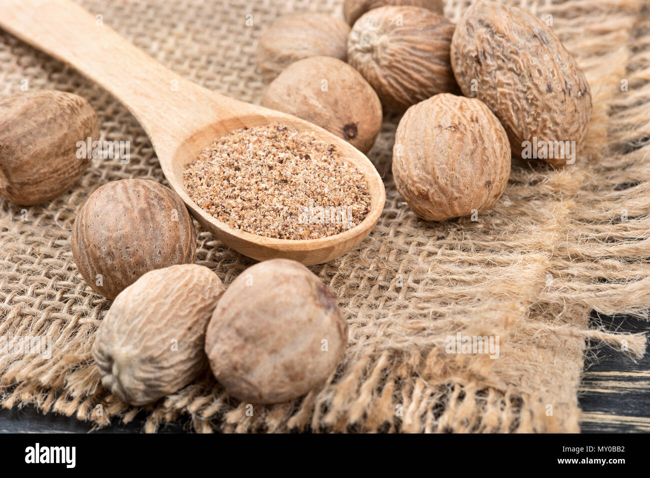 Nutmeg powder in a spoon with scattered nuts on the burlap Stock Photo ...