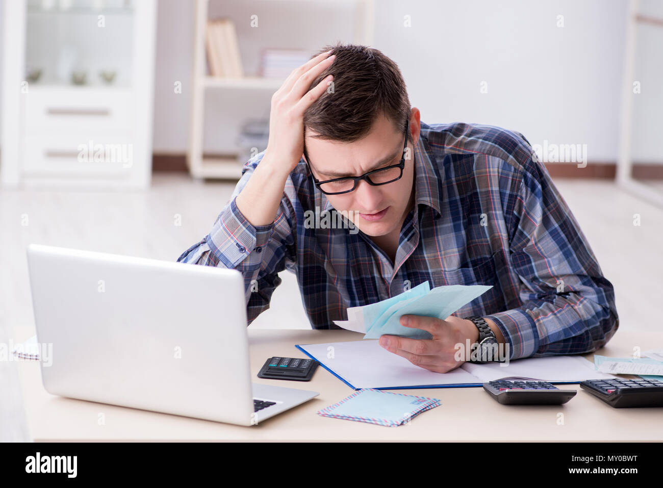 Young man frustrated at his house and tax bills Stock Photo - Alamy
