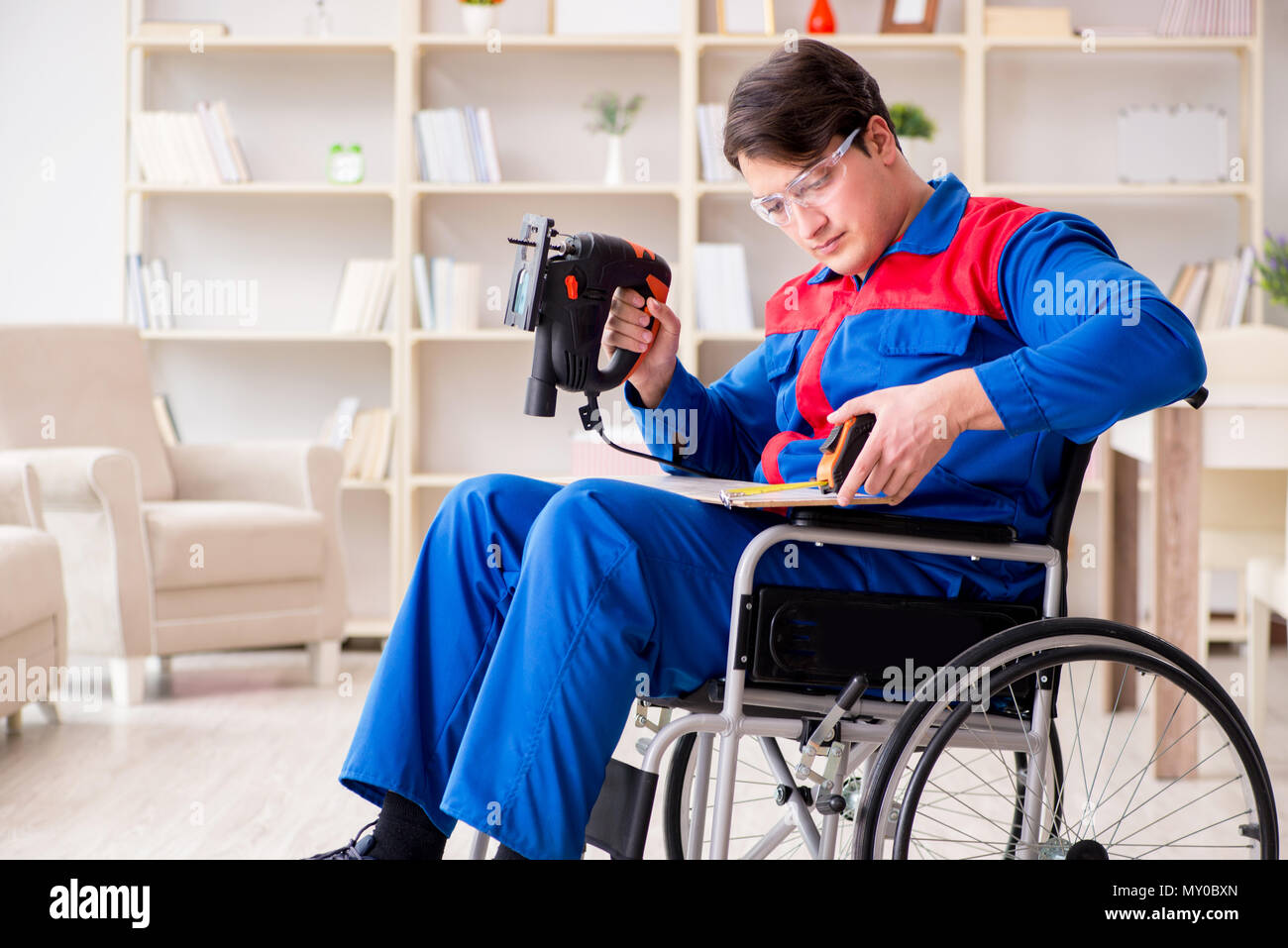 Disabled man working with handsaw at home Stock Photo - Alamy