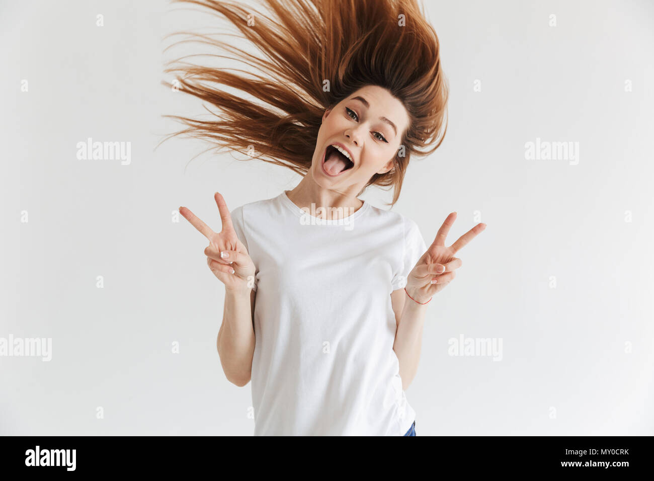 Happy screaming woman in t-shirt showing peace gestures and looking at ...