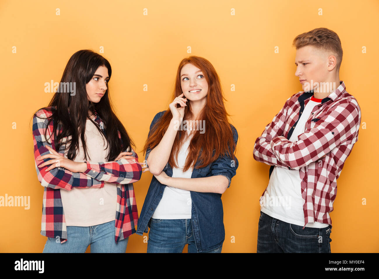 Group of confused school friends looking at each other while standing ...