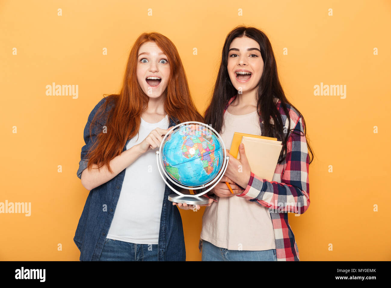Portrait of two excited young school teenage girls holding copybooks ...