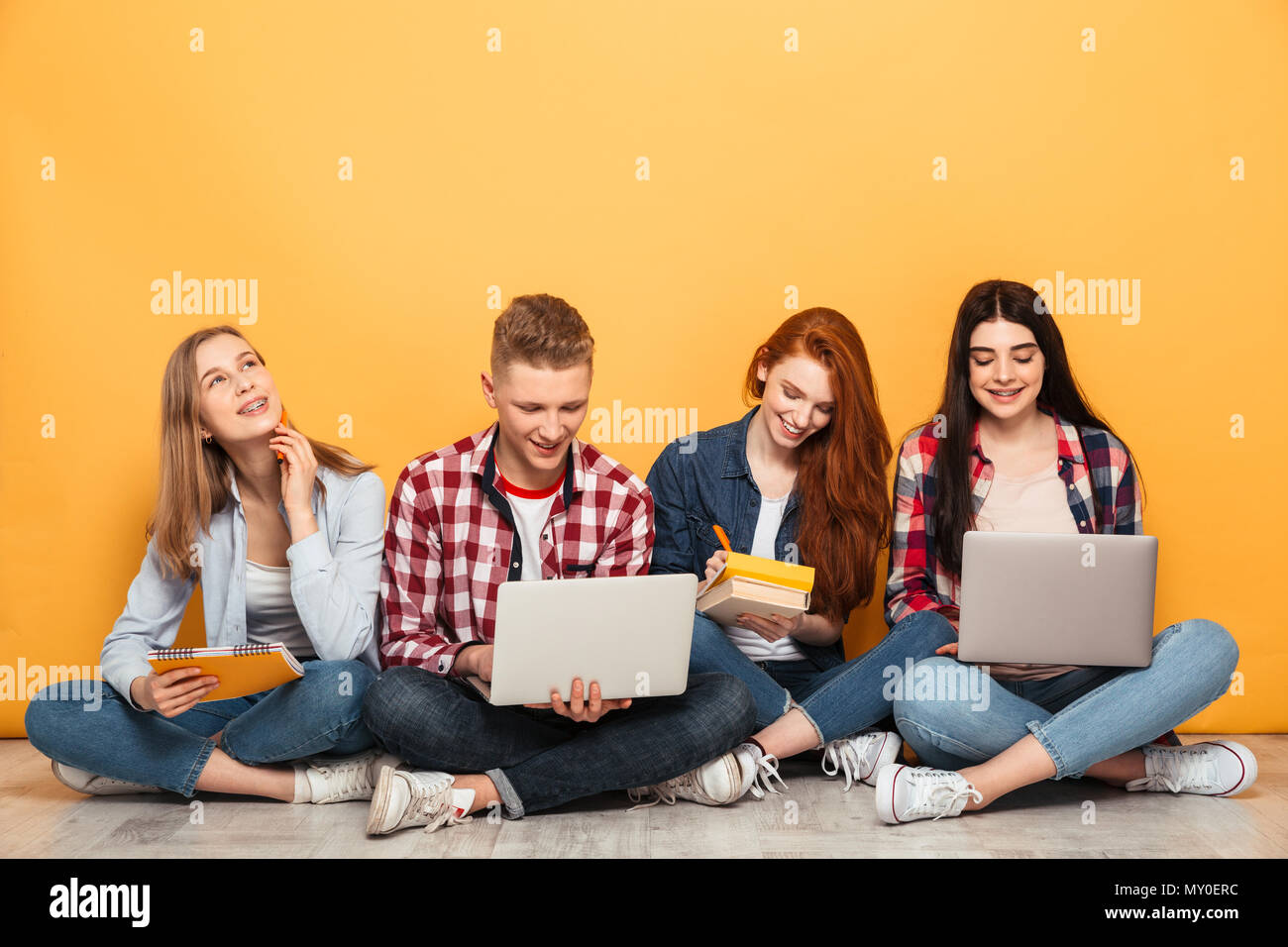 Group of young happy school friends doing homework while sitting on a ...