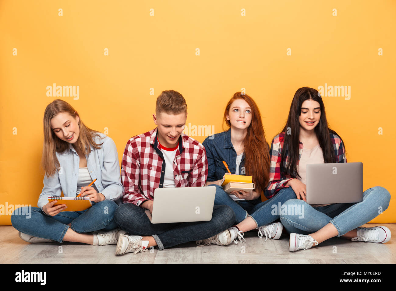 Group of young smart school friends doing homework while sitting on a ...
