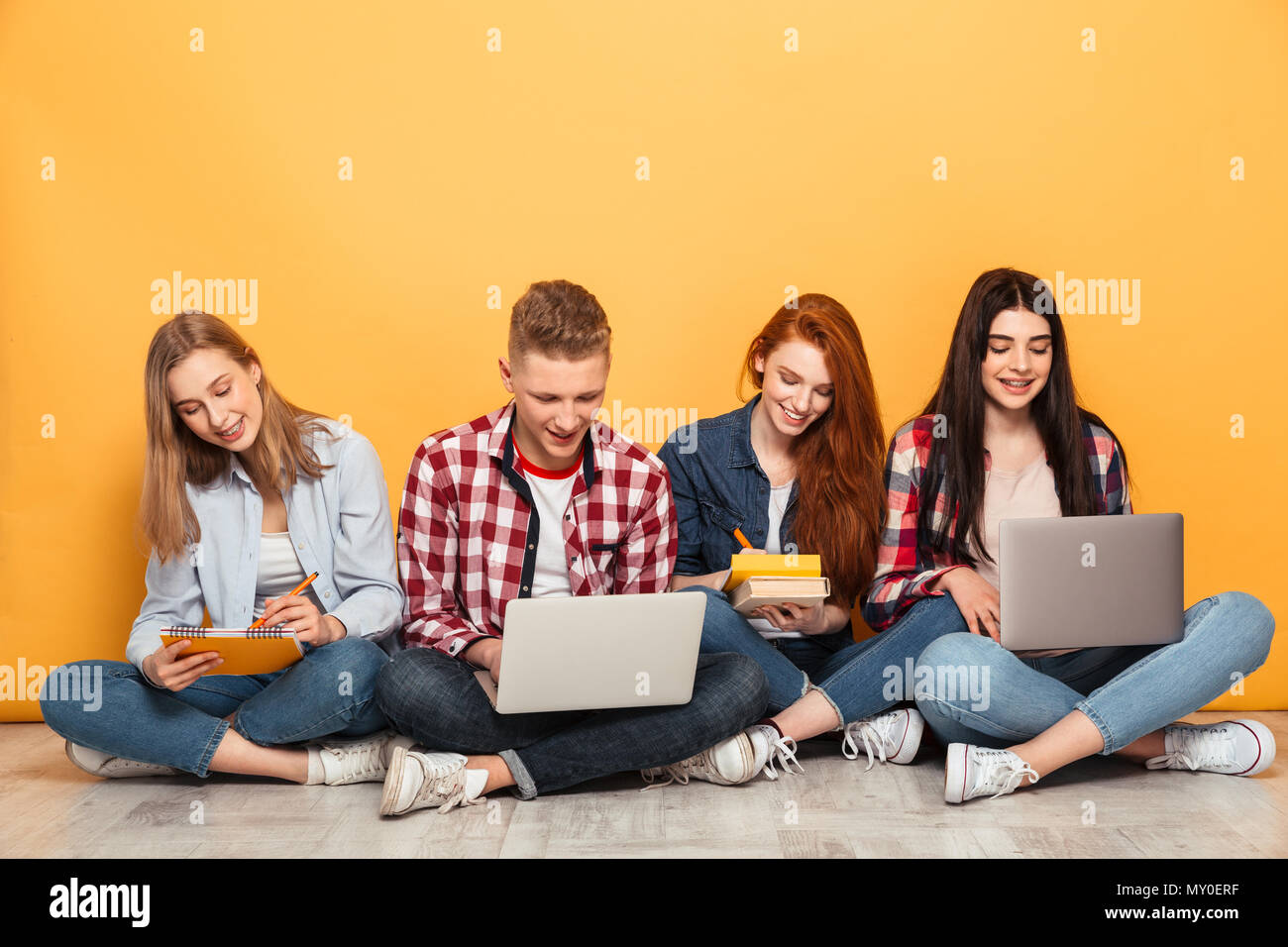 Group of happy school friends doing homework while sitting together on ...
