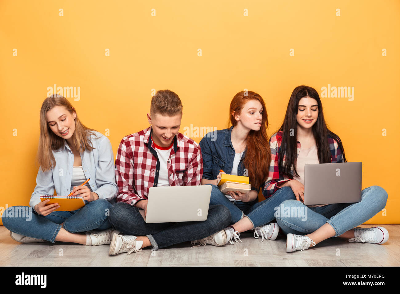 Group of satisfied school friends doing homework while sitting together ...