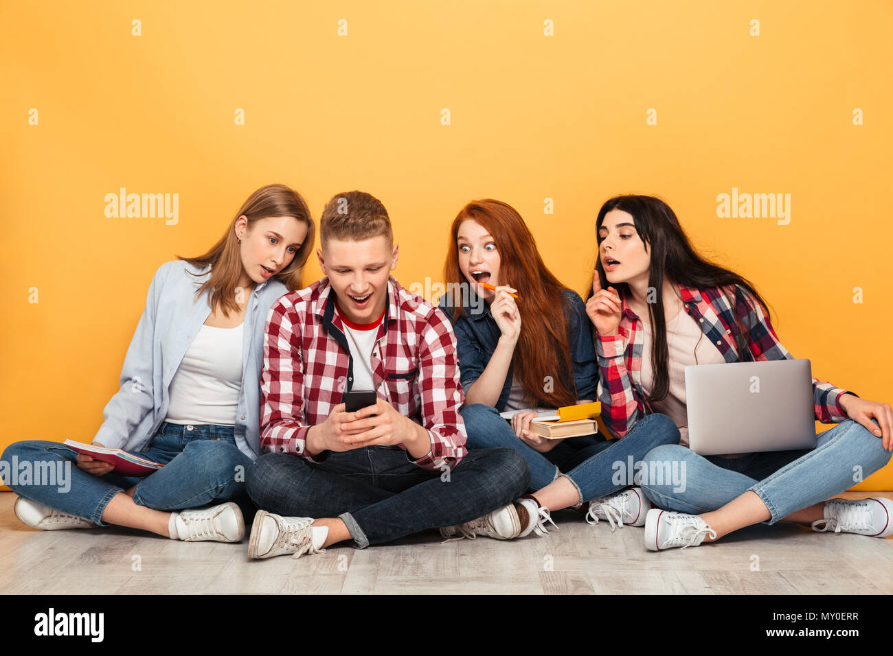 Group of young happy school friends doing homework while sitting on a ...
