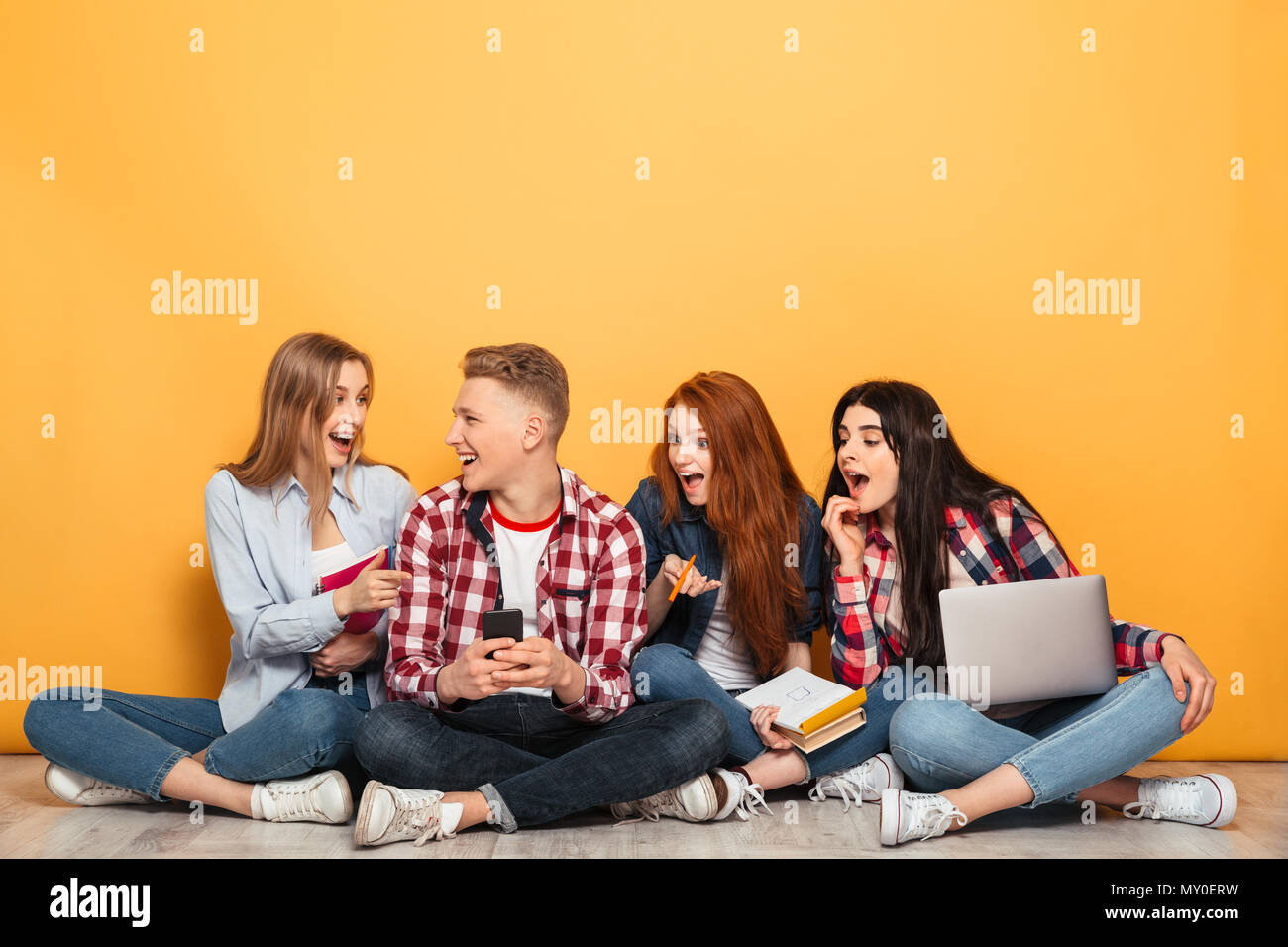Group of young positive school friends doing homework while sitting on ...