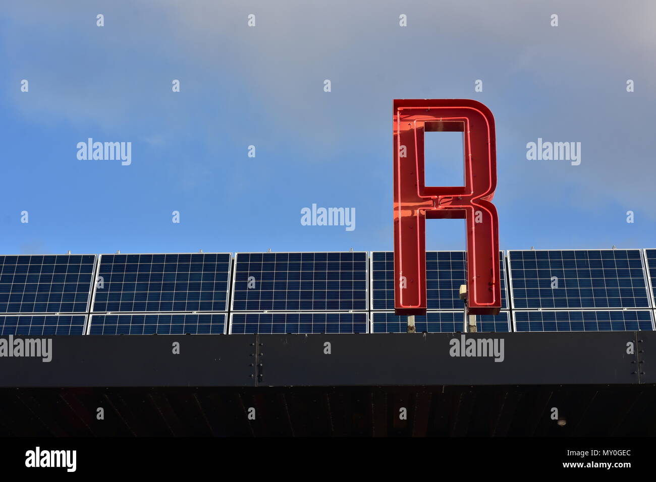 Red fluorescent tube sign letter on roof covered with solar panels ...