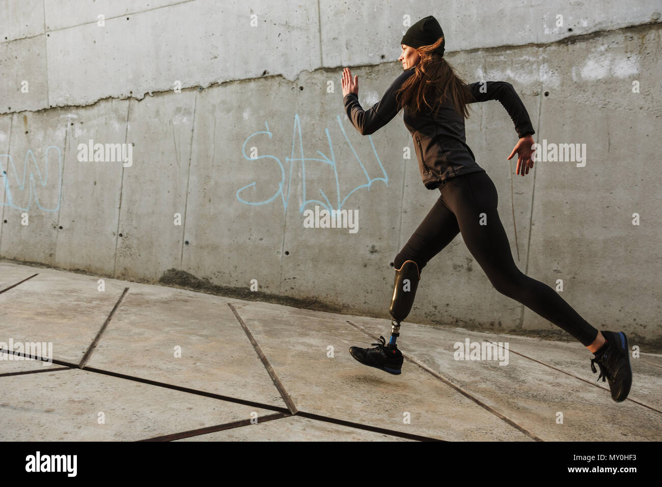 Portrait of disabled athlete woman with prosthetic leg in tracksuit ...