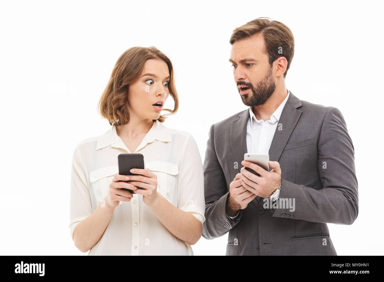 Portrait of a confused business couple holding mobile phones and ...