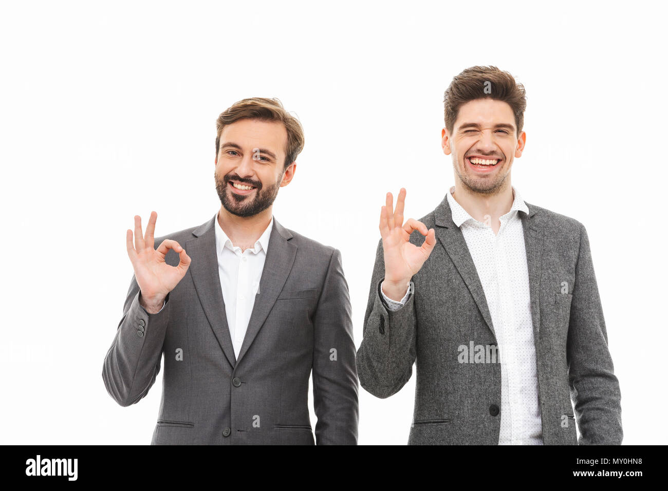 Portrait of a two satisfied business men showing ok gesture isolated ...