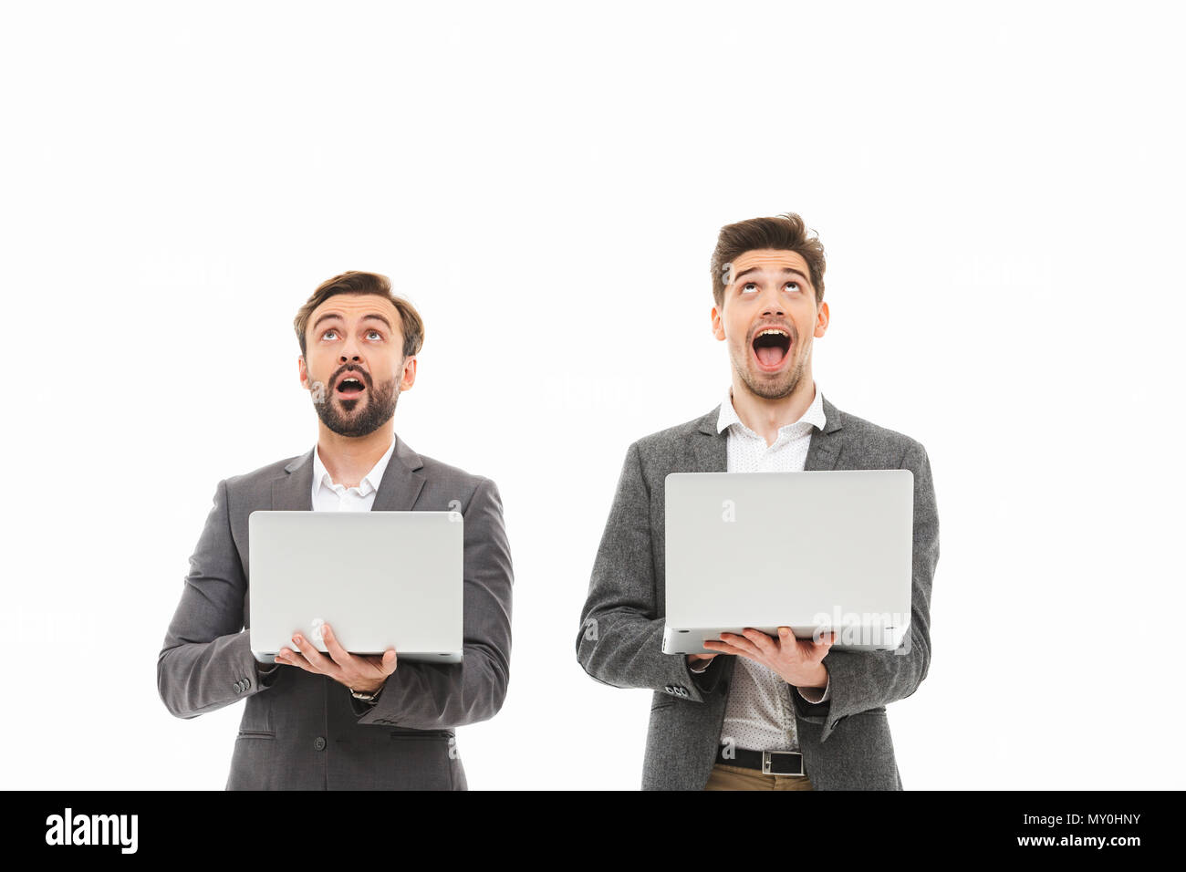 Portrait of two excited business men holding laptop computers and ...