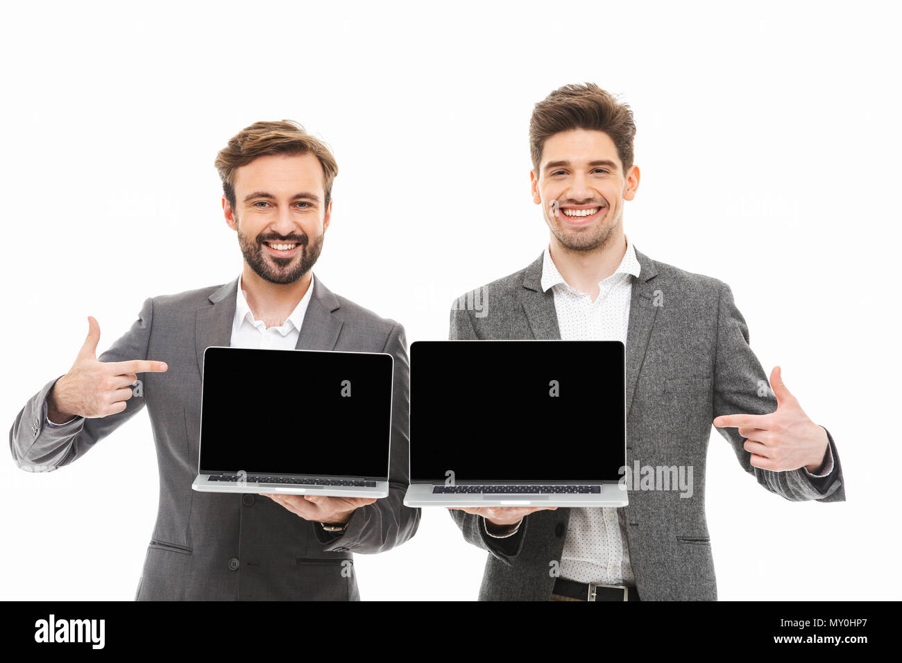 Portrait of a two happy business men pointing fingers at blank screen ...