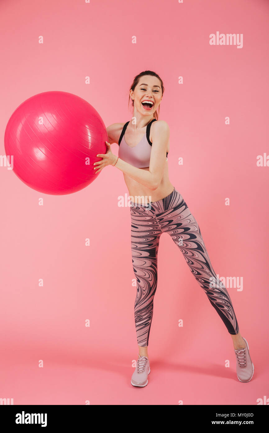 Vertical image of Playful sportswoman doing exercise with fitness ball ...