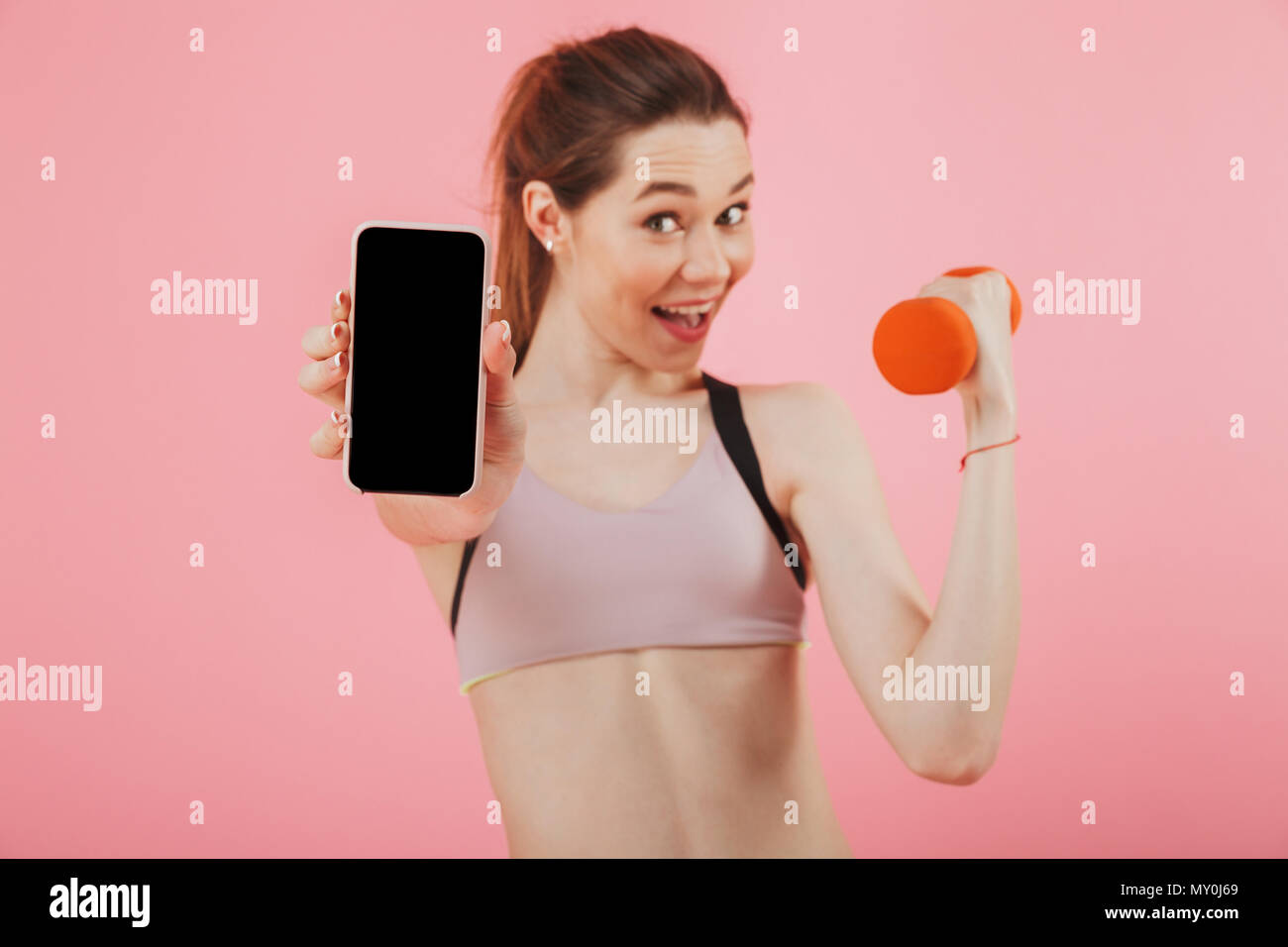 Happy sportswoman showing blank smartphone screen while doing exercise ...