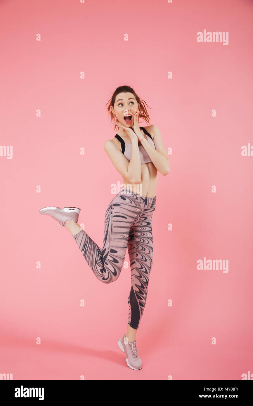 Full length image of Shocked sportswoman jumping while touching her ...