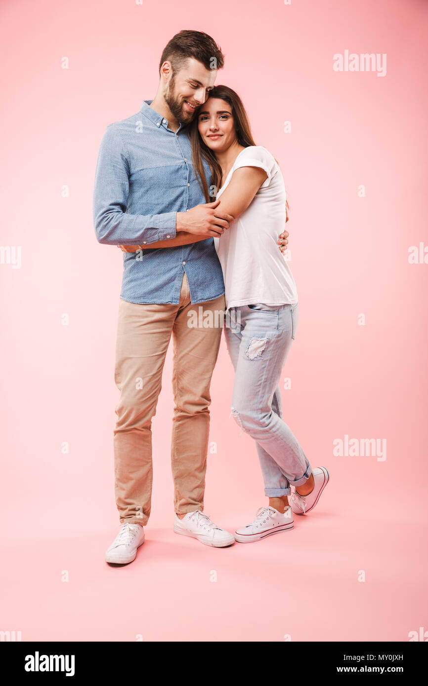 Full length portrait of a happy young couple hugging while standing ...