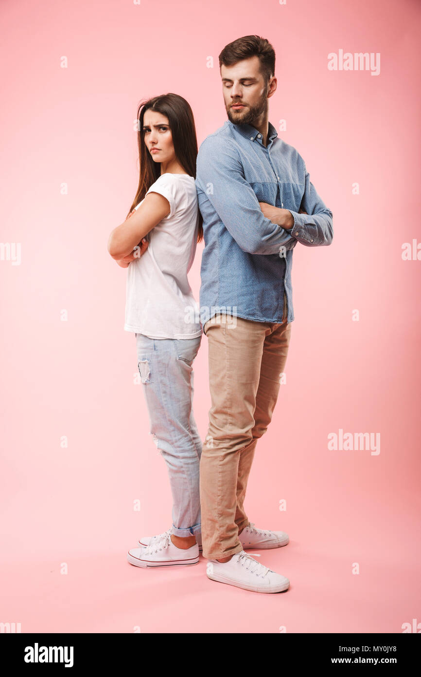 Full length portrait of an angry young couple standing back to back ...