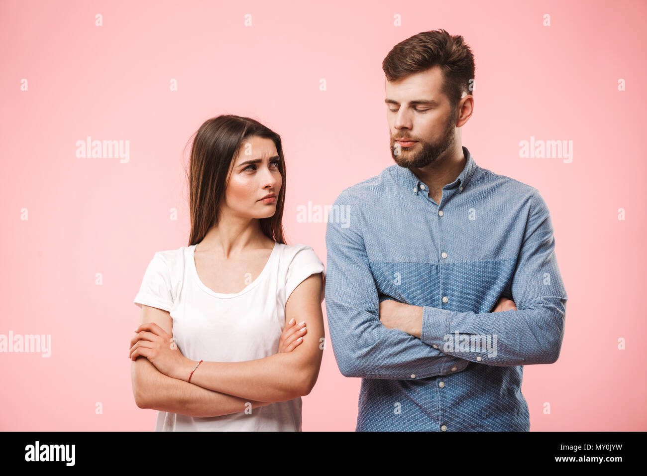 Portrait of an angry young couple standing with arms folded isolated ...