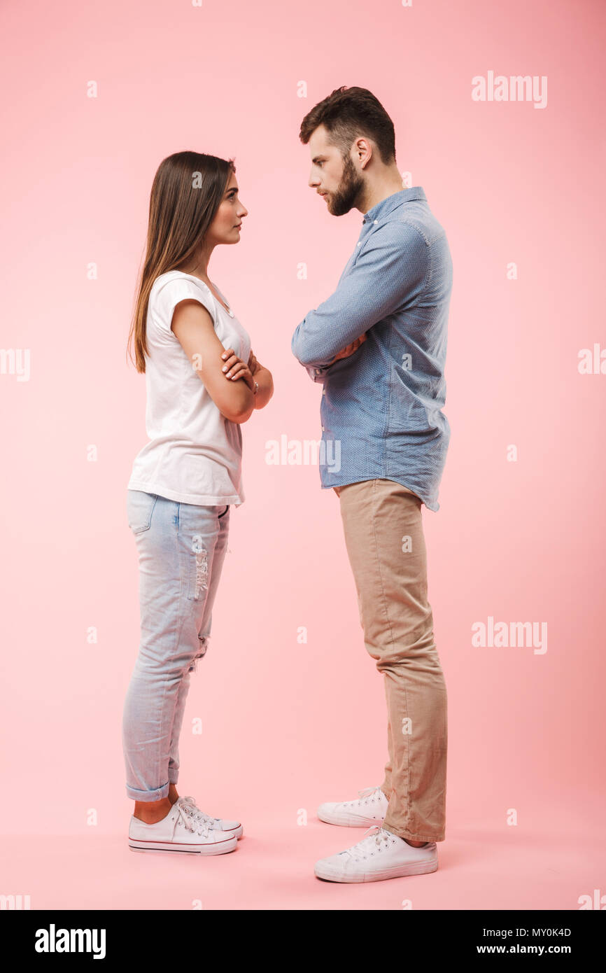 Full length portrait of an angry young couple standing with arms folded ...