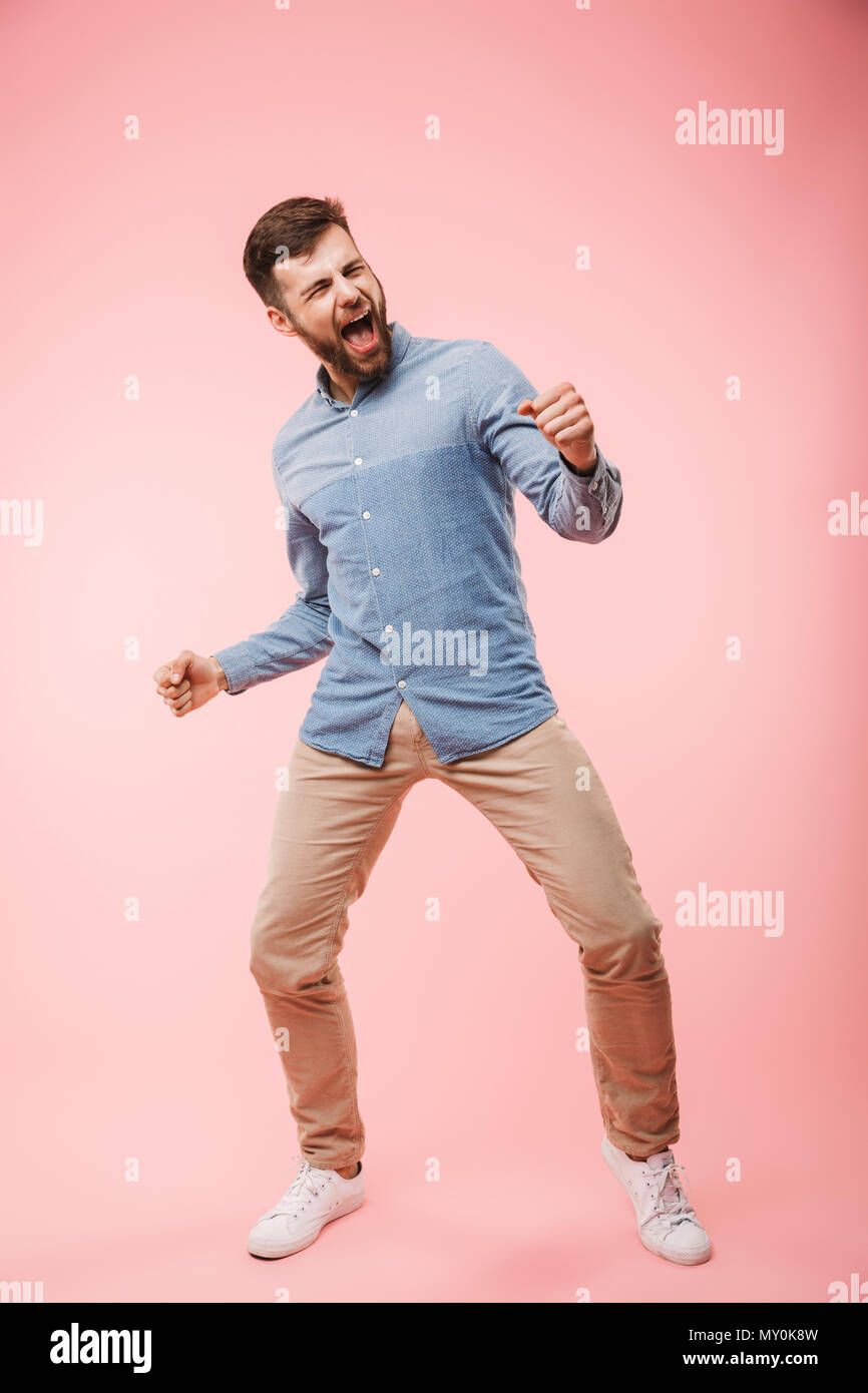 Full length of a cheerful young man standing and celebrating success ...
