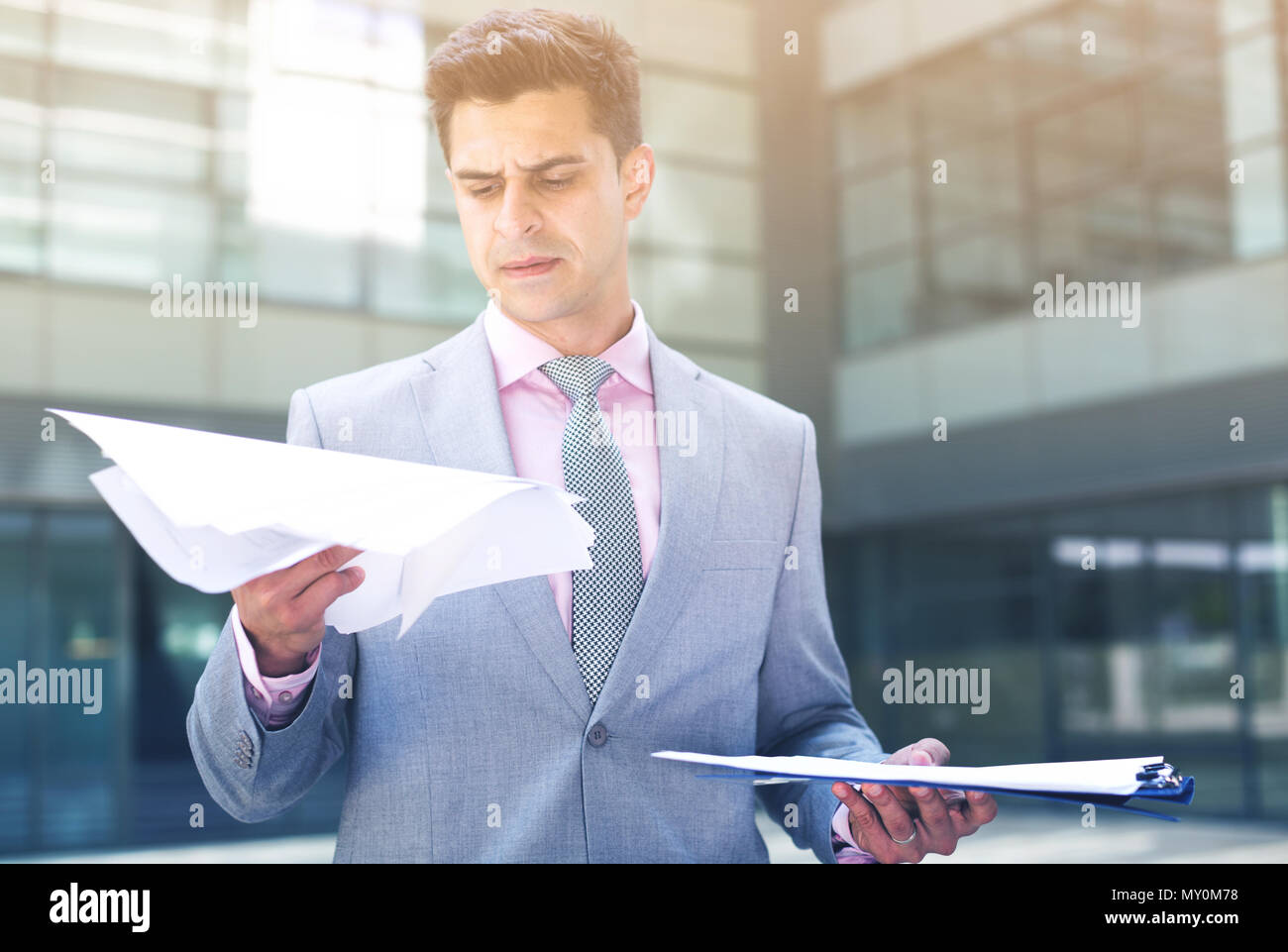 Businessman holding folder with documents and attentively reading Stock ...