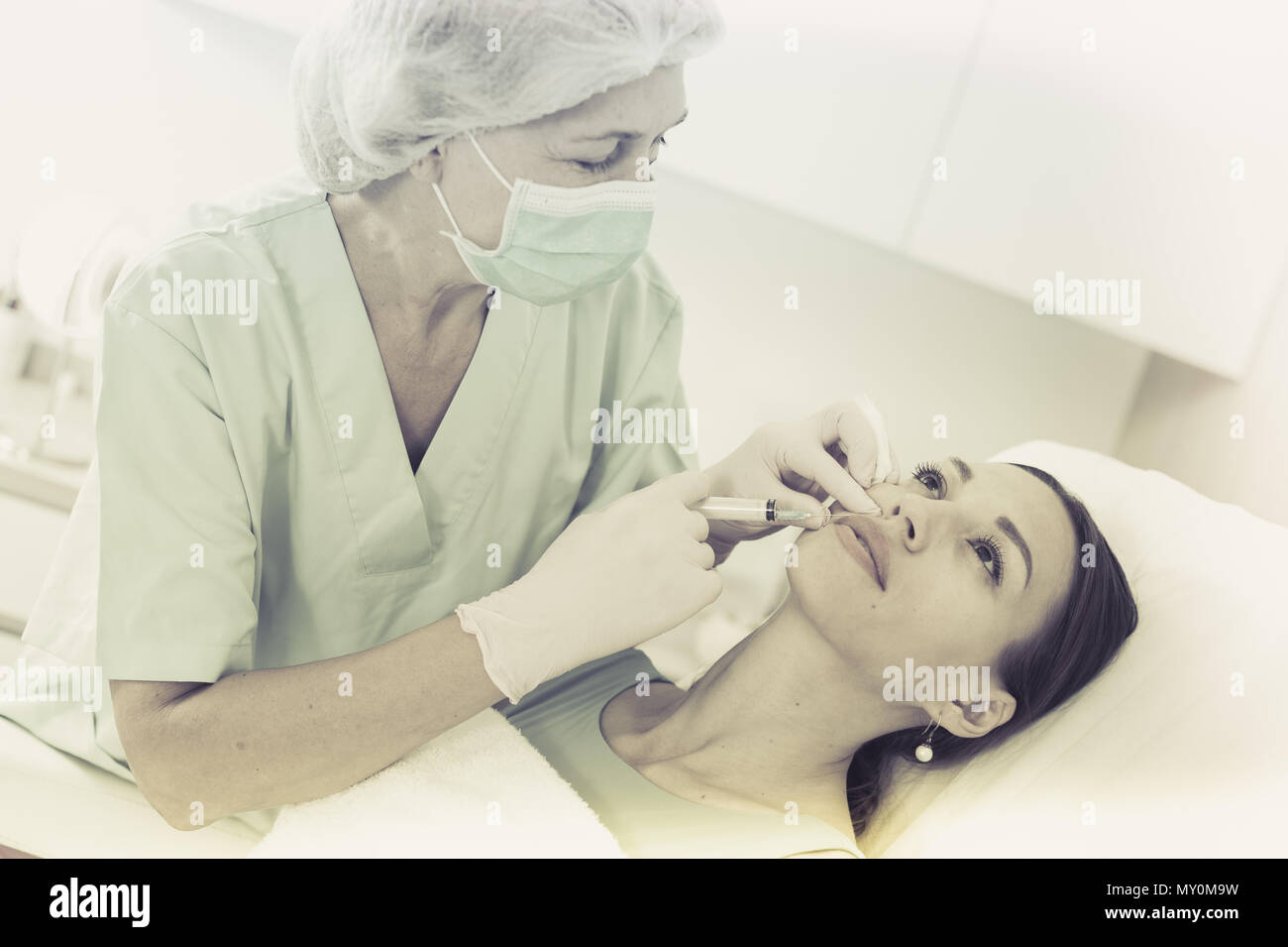 Young woman getting injection for facial correction procedure in ...