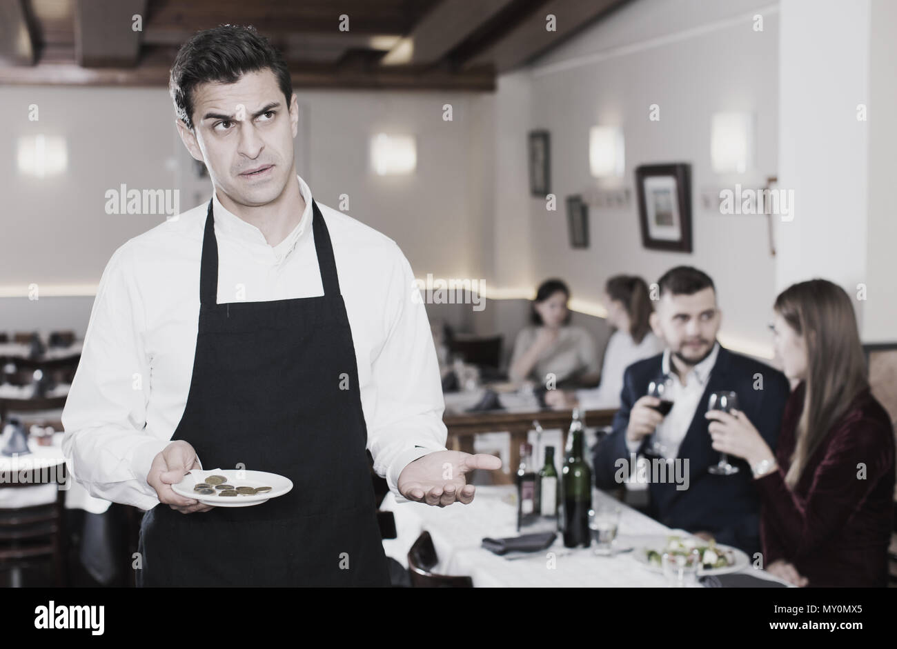 Portrait of waiter dissatisfied with small tip from restaurant visitors ...