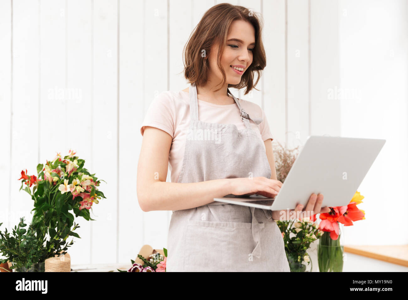Beautiful sales woman standing near bouquets in flower workshop and ...