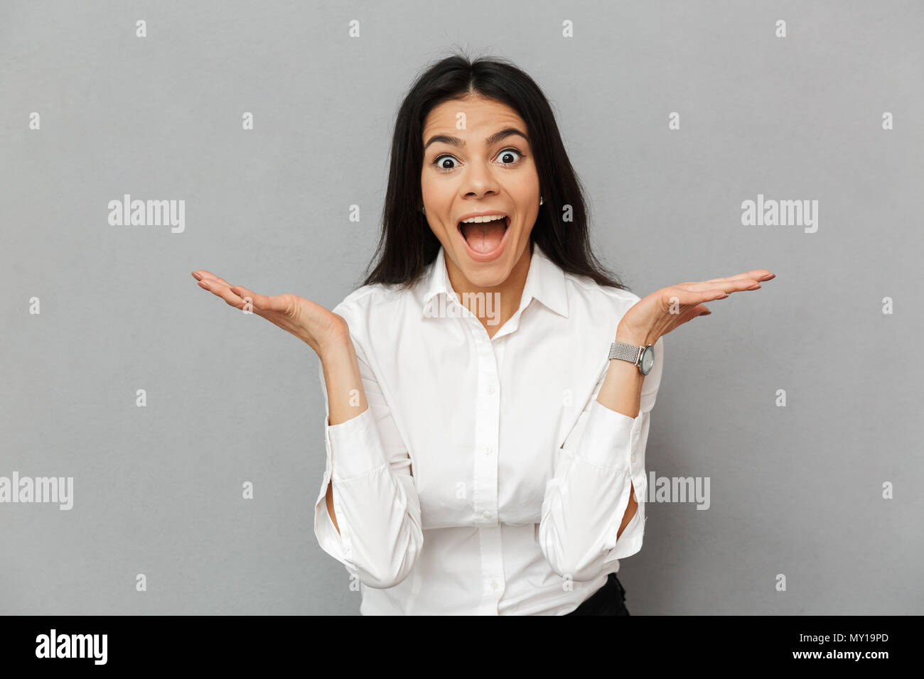 Portrait of excited or surprised woman wearing white shirt screaming ...