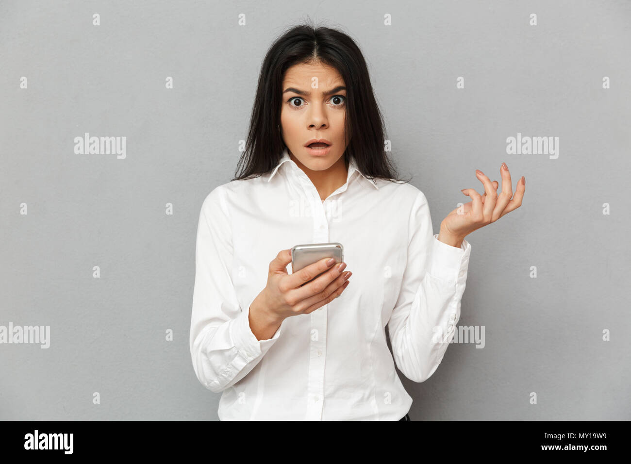 Photo of shocked or outraged woman 30s in formal wear looking on camera ...