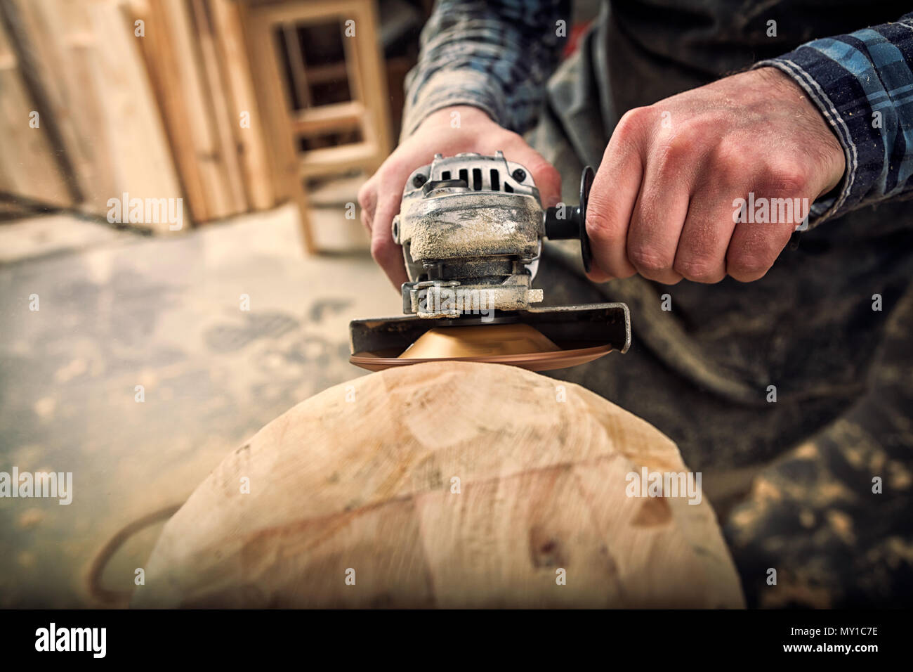 Close up of a young man carpenter in a suit, goggles saws a man's head ...