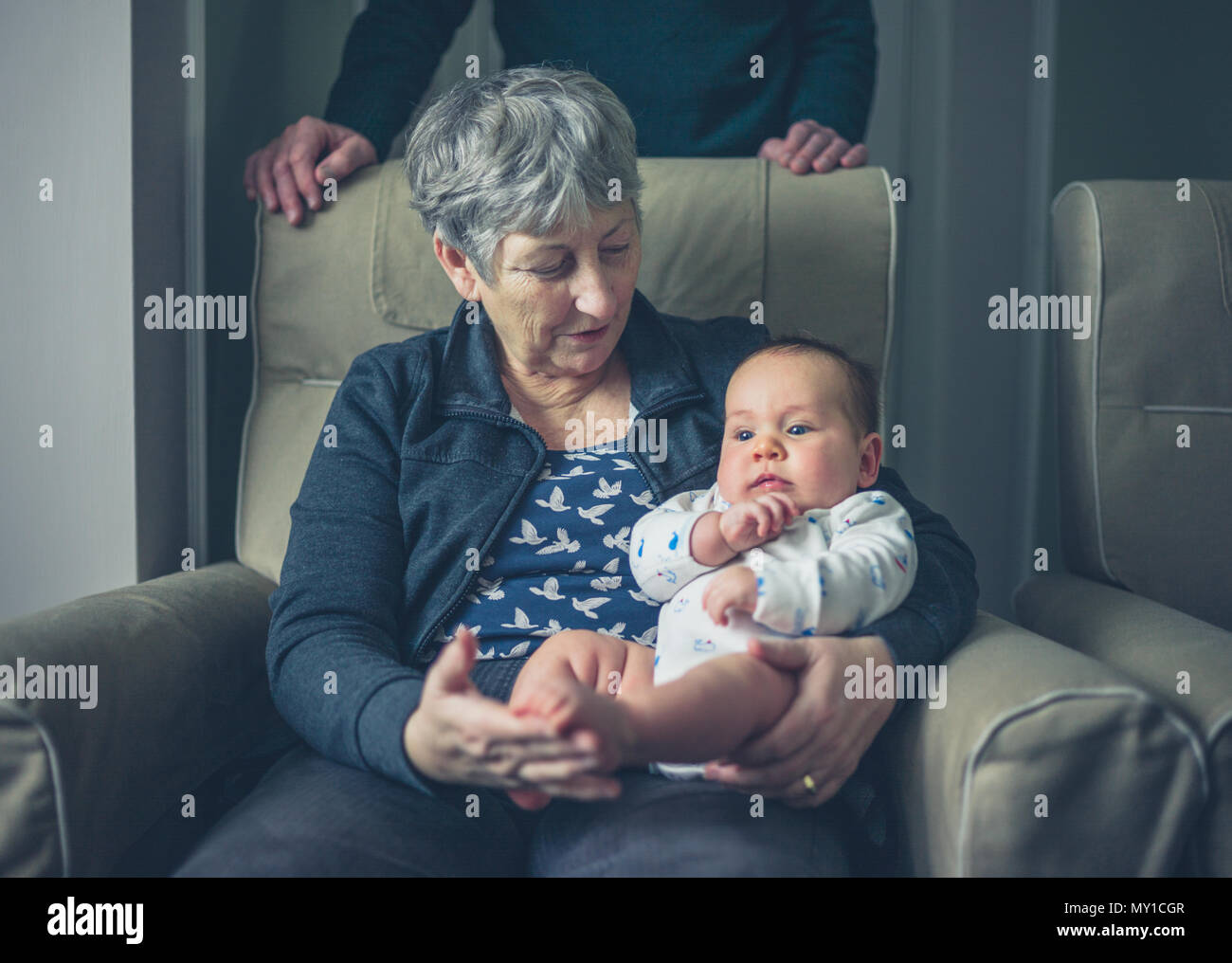 Grandparents relaxing at home with their baby grandchild Stock Photo ...