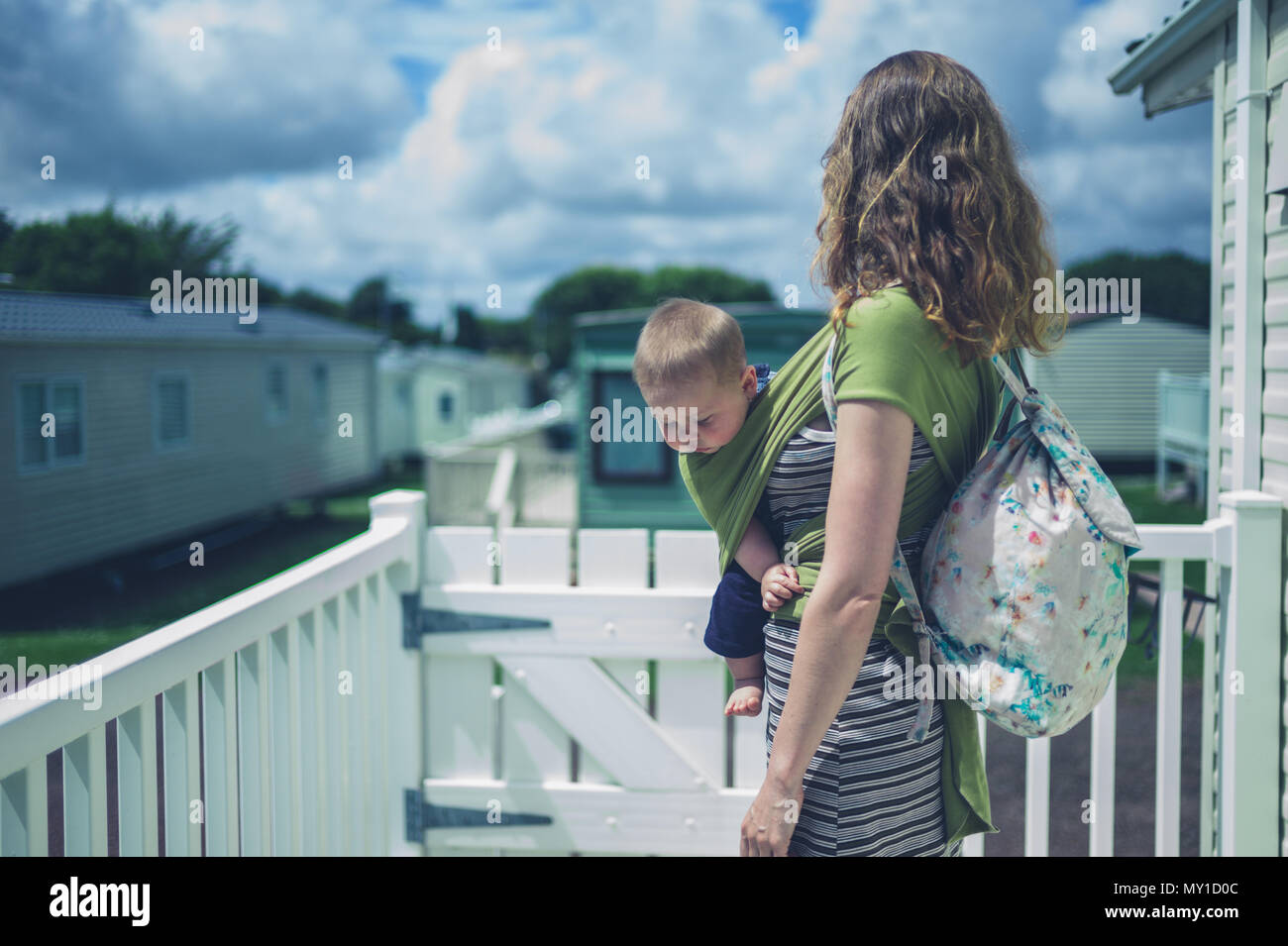 A young woman is standing outside a caravan in a trailer park with her ...