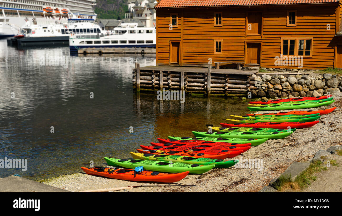Colorful canoes along the beach in front of a brown house. Ferries and ...