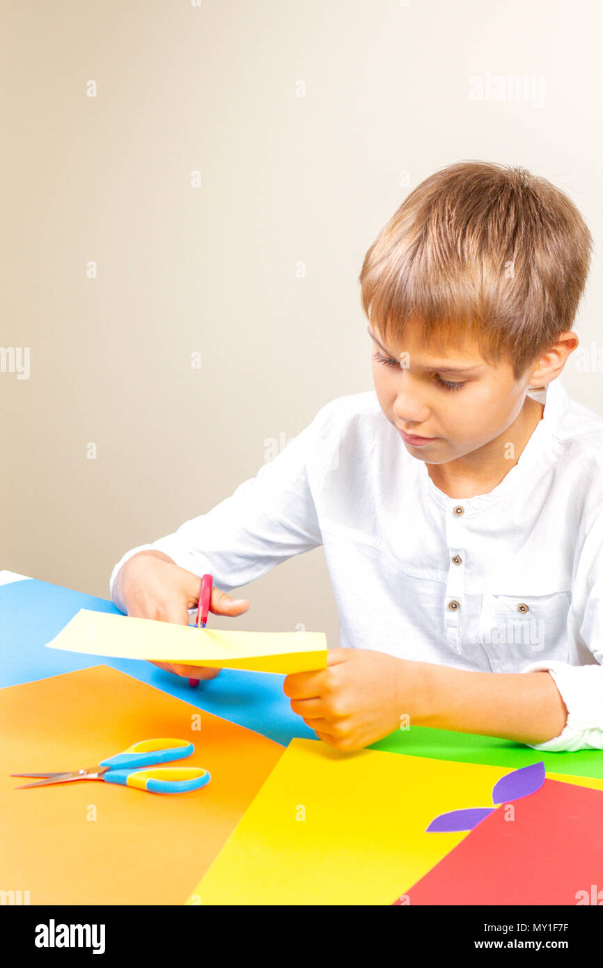 Child cutting colored paper with scissors at the table Stock Photo - Alamy